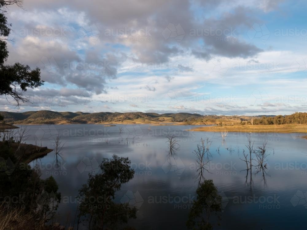 Image of Windamere Dam with trees reflected in the water - Austockphoto