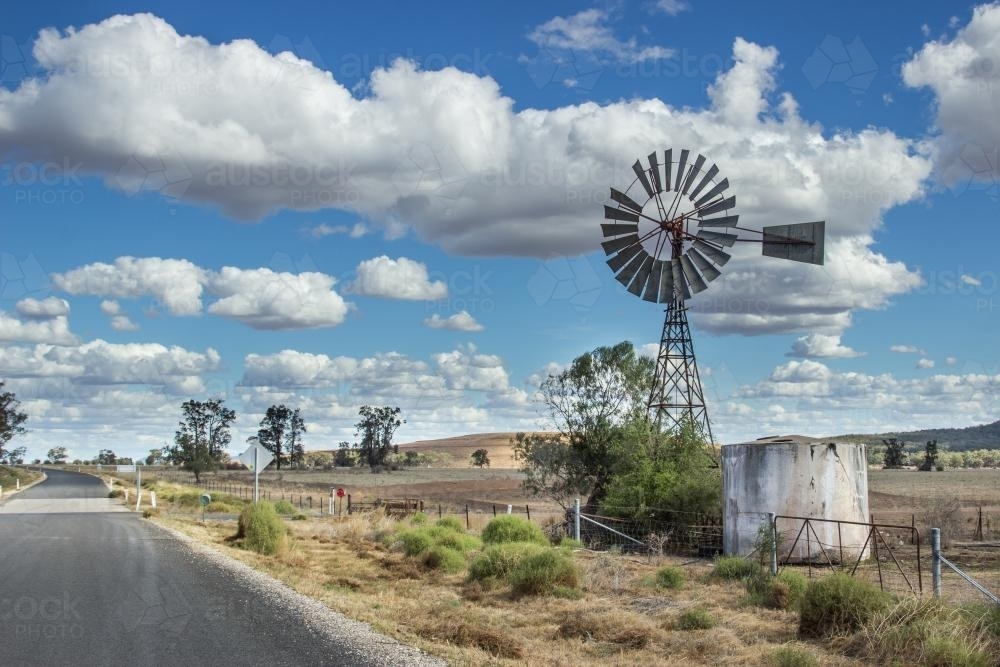 Image of Windmill and water tank in a paddock - Austockphoto