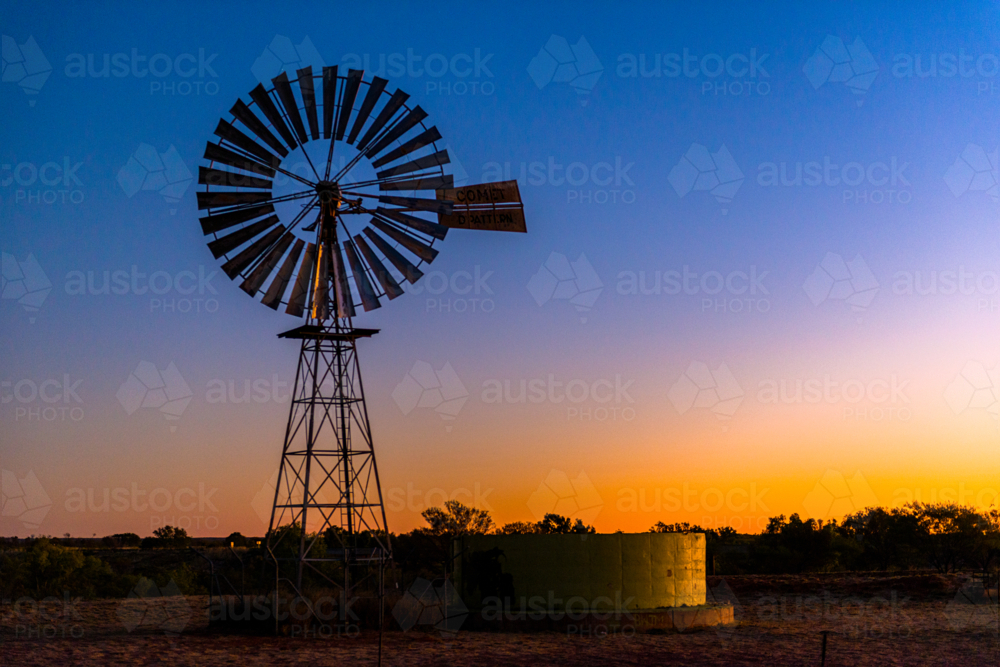 Image of Windmill at sunset over the red dirt plains. - Austockphoto