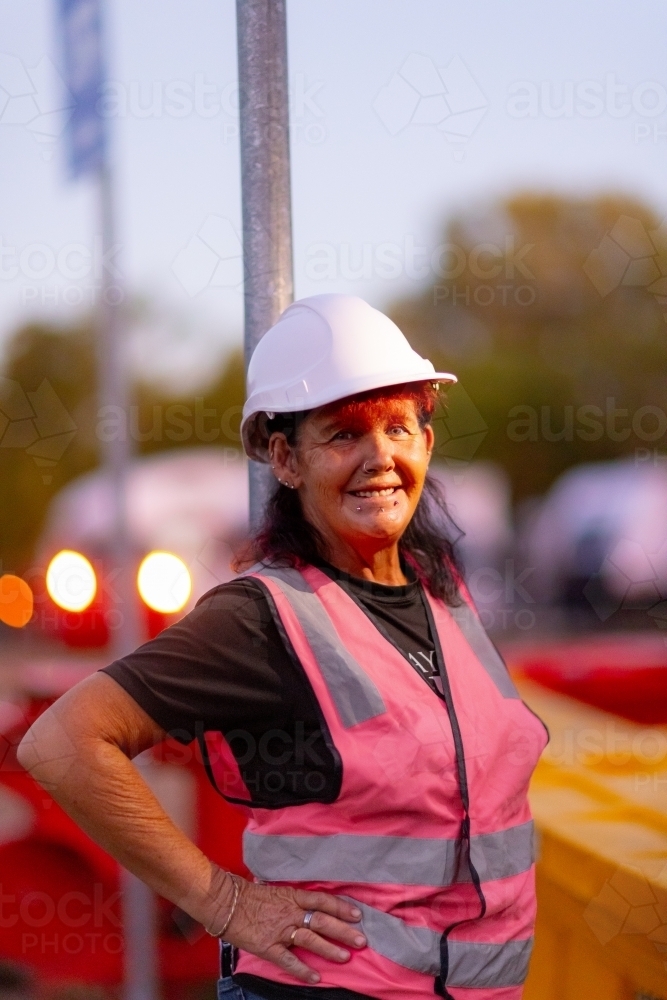 Image of woman in her 50s on industrial site wearing hi-vis and a hard hat - Austockphoto