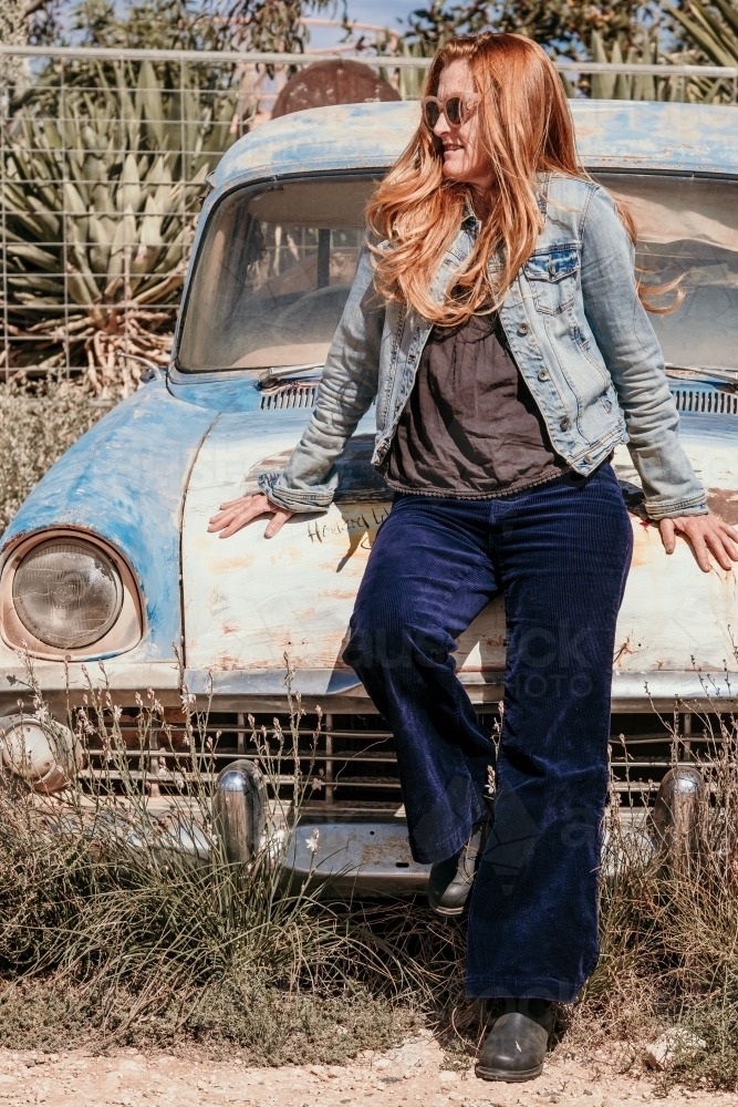 Image of Woman leans against old car. - Austockphoto