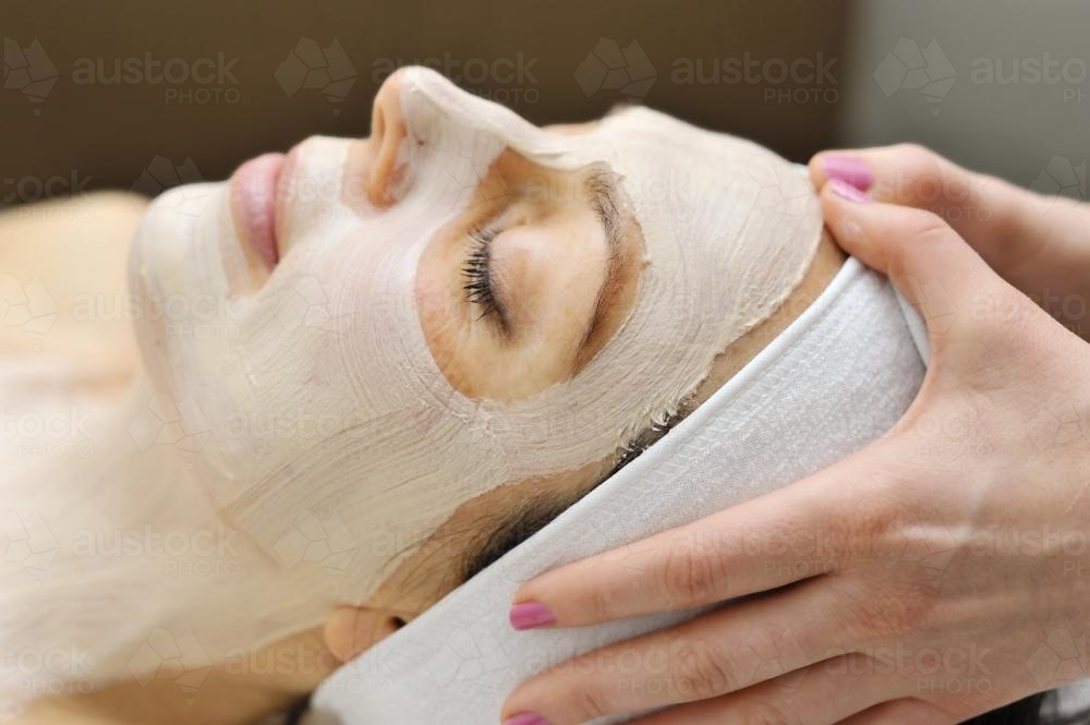 Image of Woman relaxes as a beautician applies a fask mask during a ...