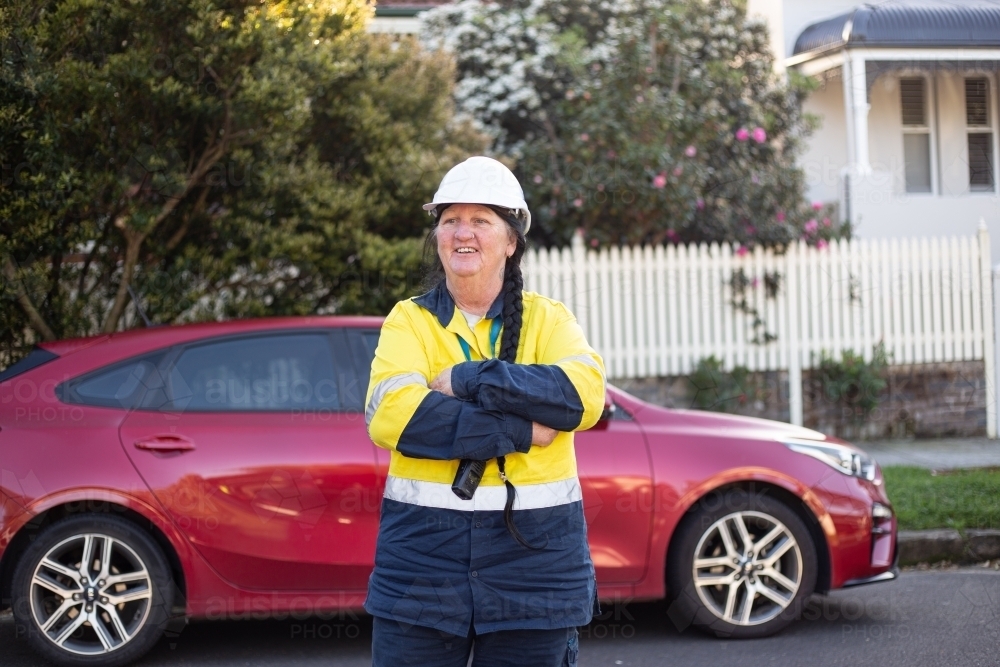 Image of woman road worker crossing her arms in front of a red car ...