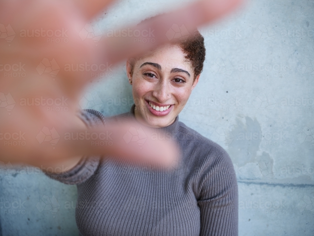 Image of Woman sitting against a concrete wall reaching out - Austockphoto