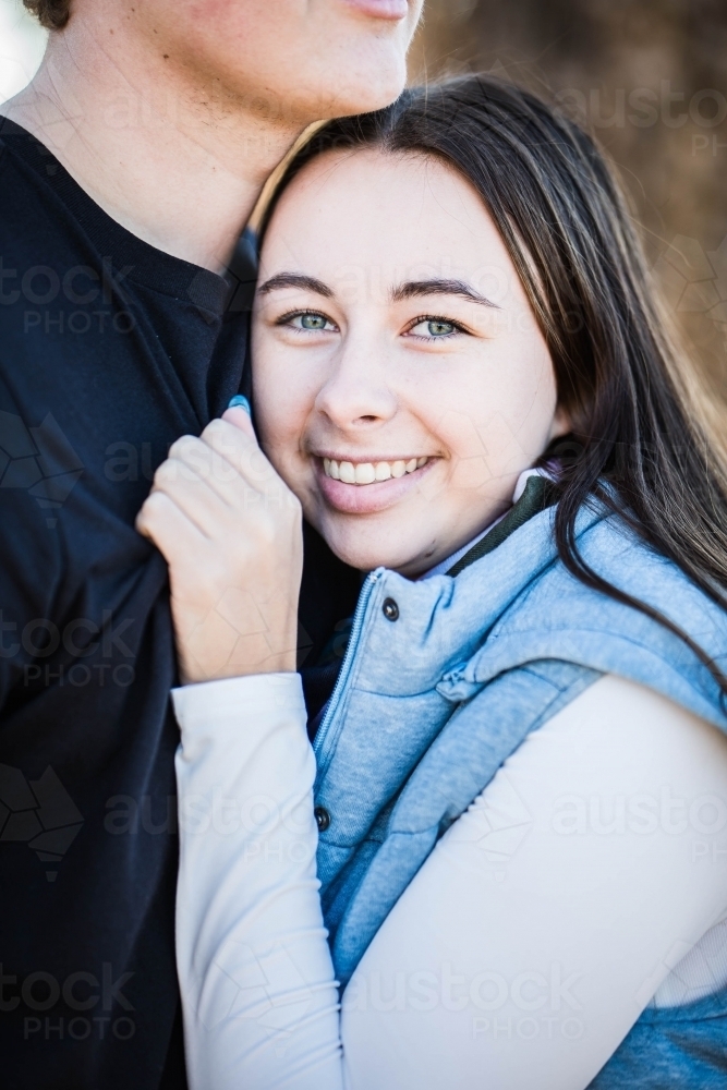 Image of Woman snuggled in to boyfriend's chest smiling hand clutching ...