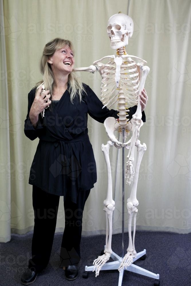 Image of Woman standing and laughing with skeleton - Austockphoto