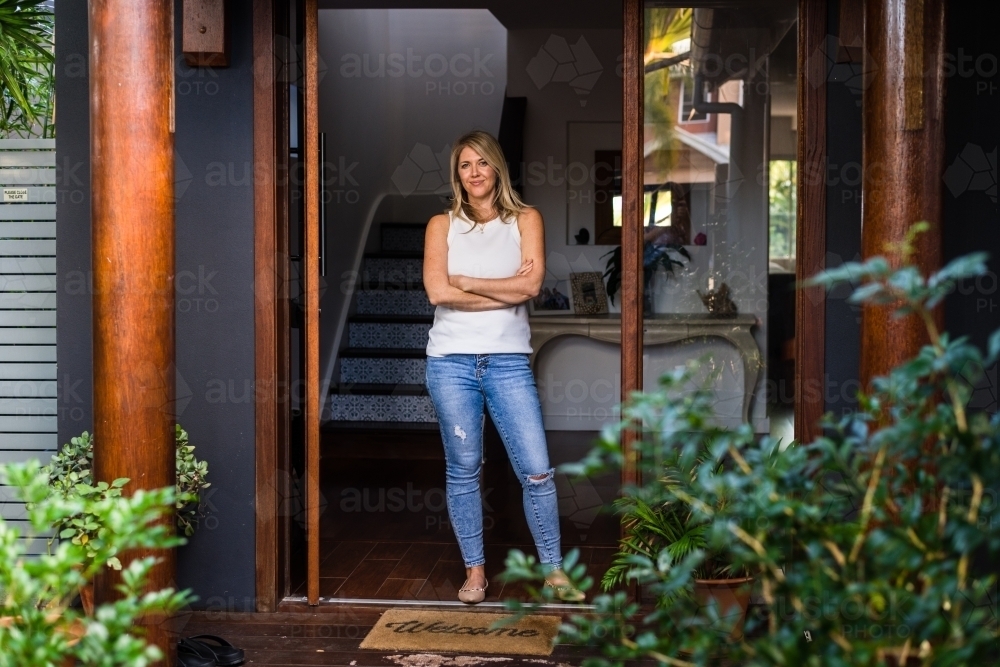 Image of woman standing at the front door of her home - Austockphoto