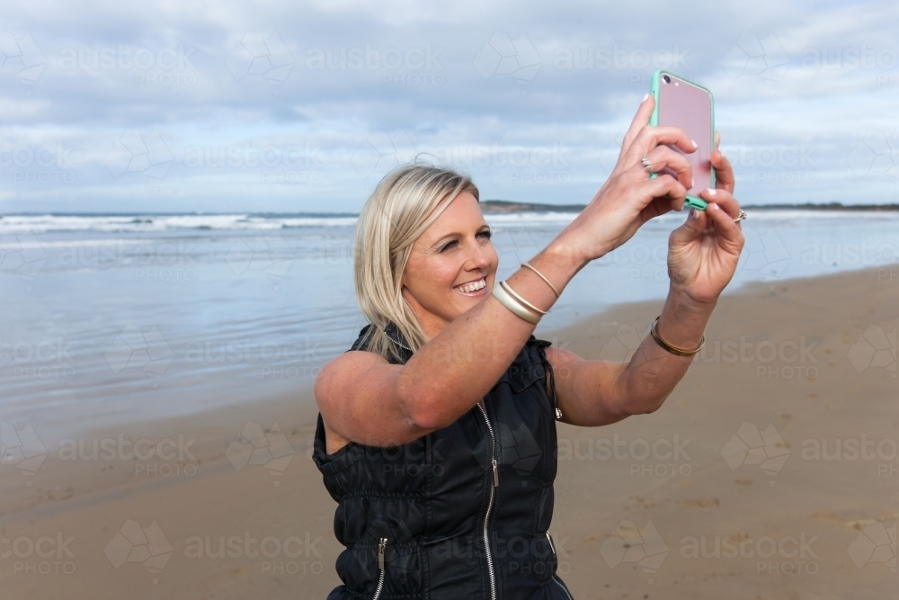 Image of Woman taking a selfie at the beach - Austockphoto