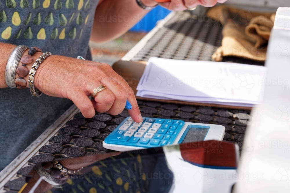 image-of-woman-using-a-calculator-to-add-up-numbers-and-amounts-austockphoto