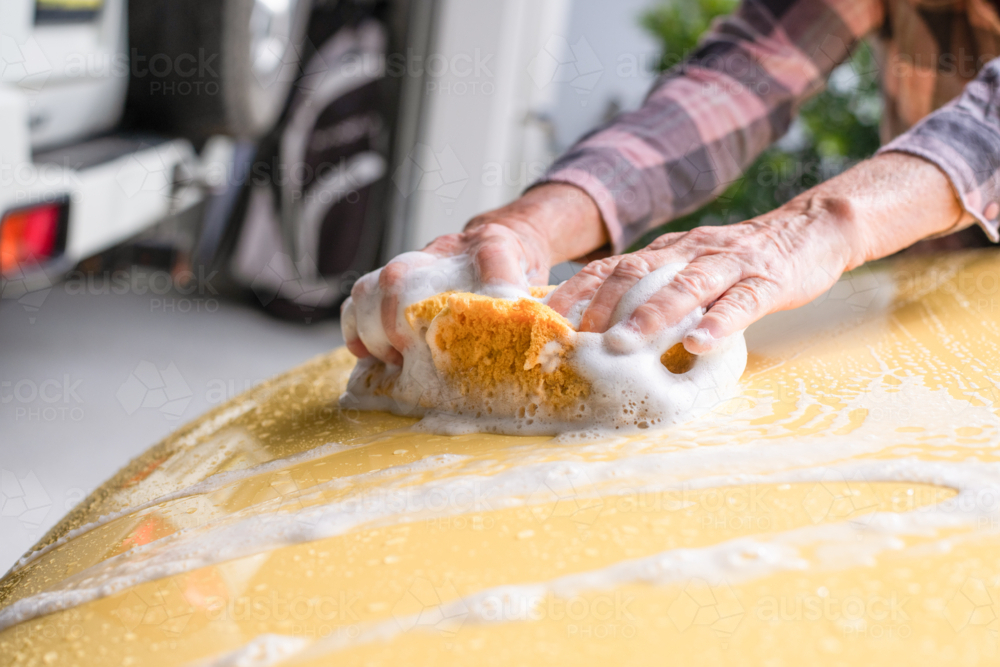 Image of woman washing her car with a soapy sponge - Austockphoto