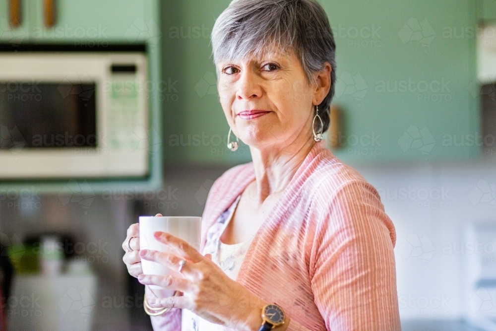 Image of Woman with a neutral content expression standing with mug in ...