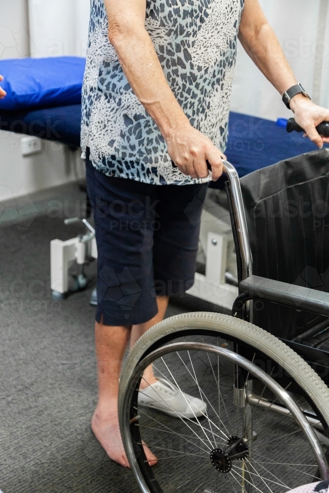 Image of Woman with leg injury standing beside wheelchair - Austockphoto