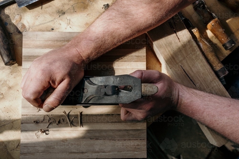 Image of Woodworkers hands planing timber. - Austockphoto