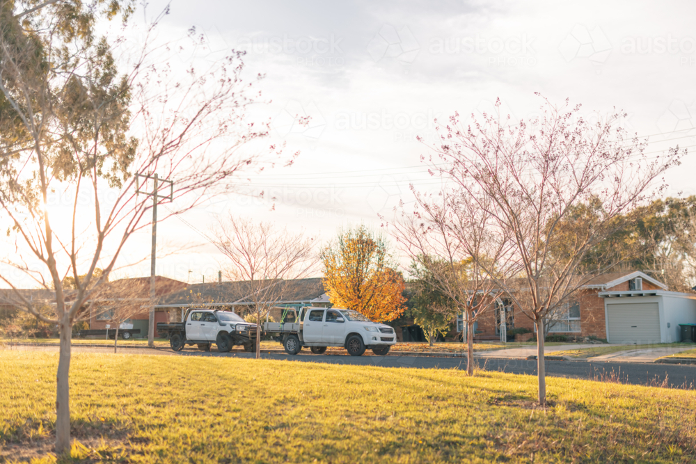 Image of Work vehicles parked along a quiet small regional town street ...