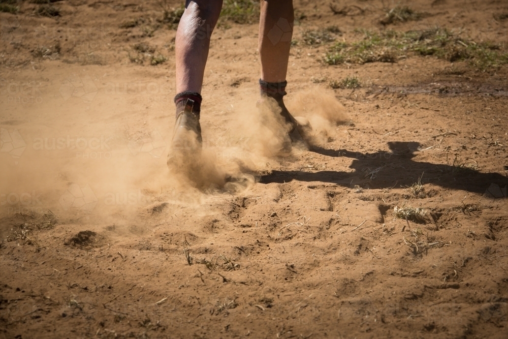 Image of Workboots walking on dusty dry ground - Austockphoto