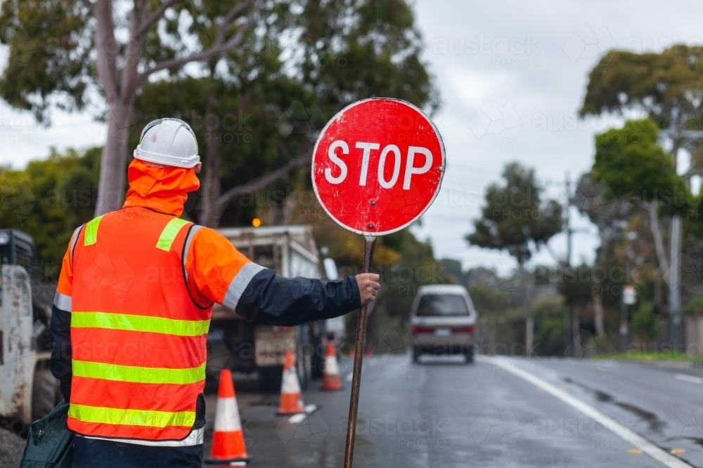 Image of worker holding roadwork stop sign - Austockphoto