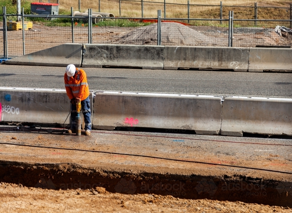 Image of Worker on building site digging hole with machinery - Austockphoto