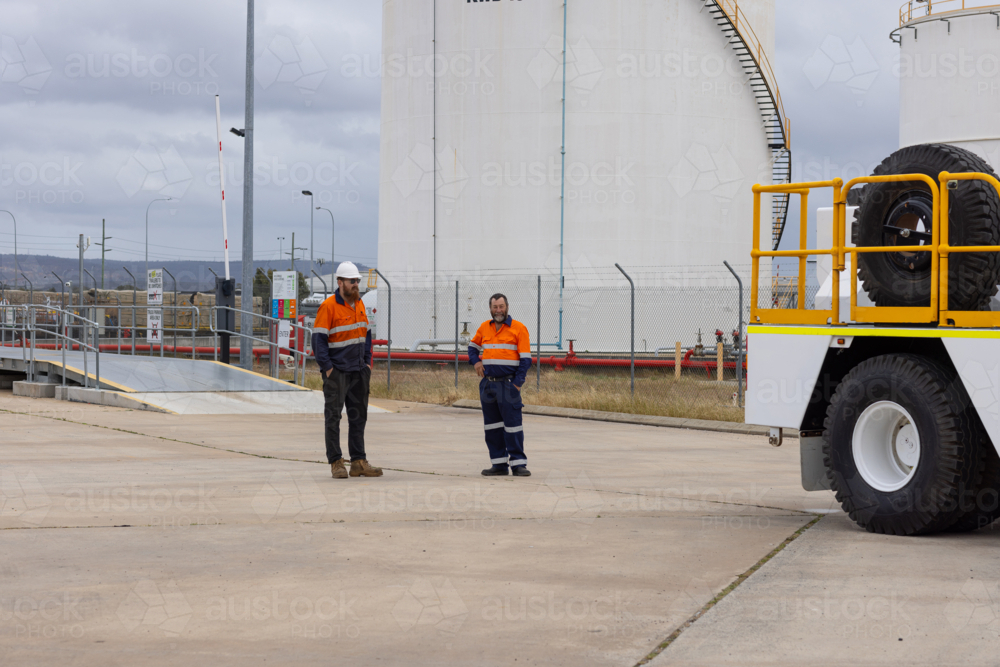 Image of Workers standing behind crane truck on industrial site ...