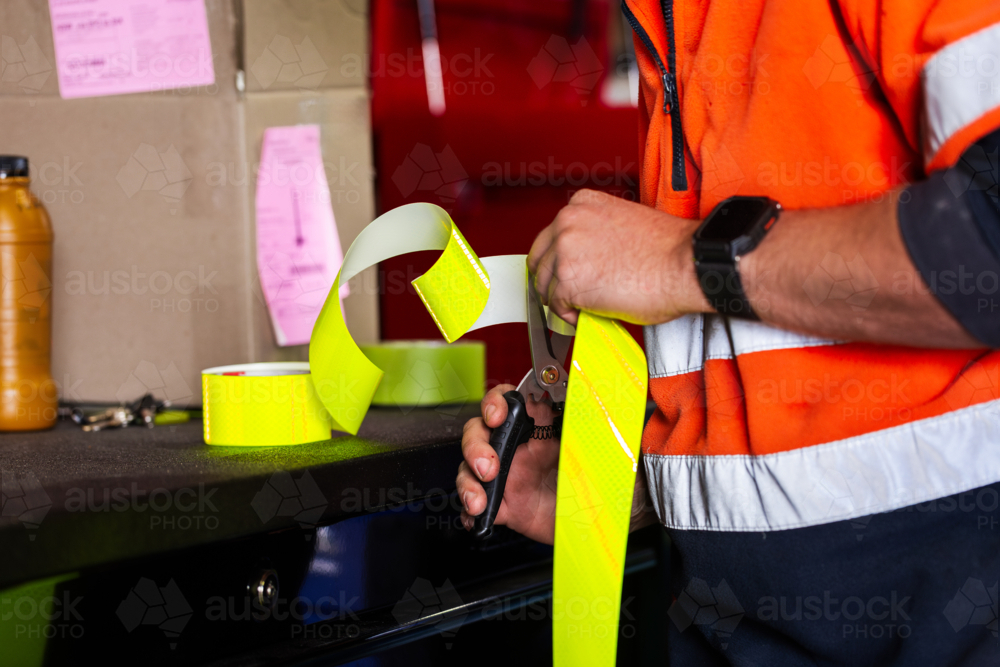 Image of Workman cutting reflective tape for installation on mining ...