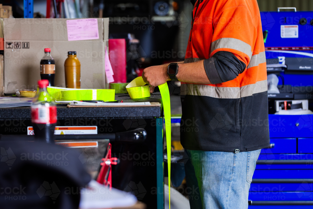 Image of Workman cutting reflective tape for installation on mining ...