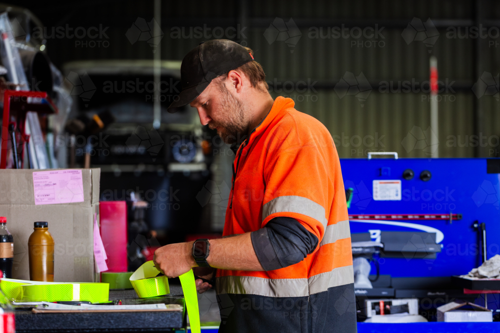 Image of Workman cutting reflective tape for installation on mining ...