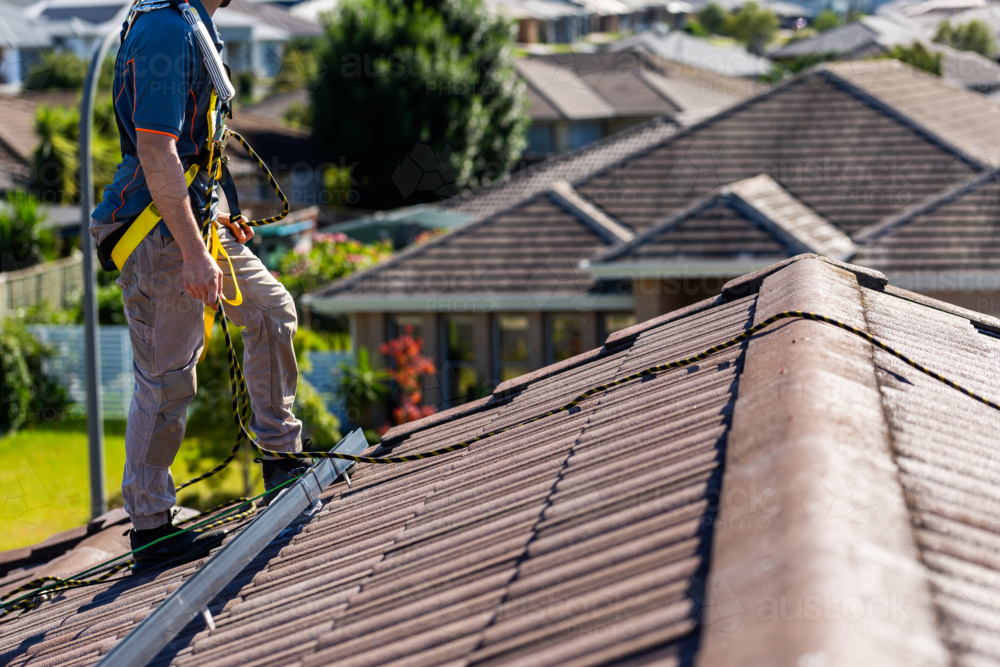 Image of Workman labourer climbing on roof of house wearing PPPE safety ...
