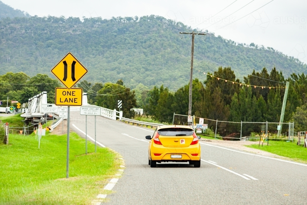 Image of Yellow p plate car driving down rural road - Austockphoto