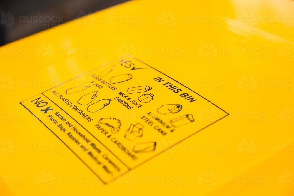 Image of yellow recycling bin information on the lid - Austockphoto