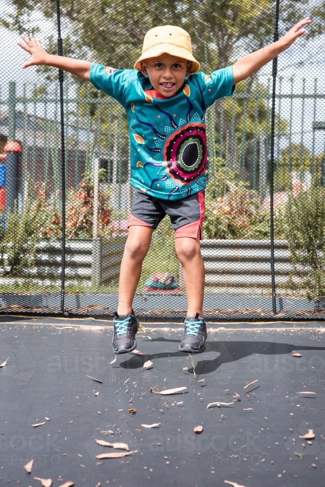 Image of Young Aboriginal boy jumping in schoolyard - Austockphoto