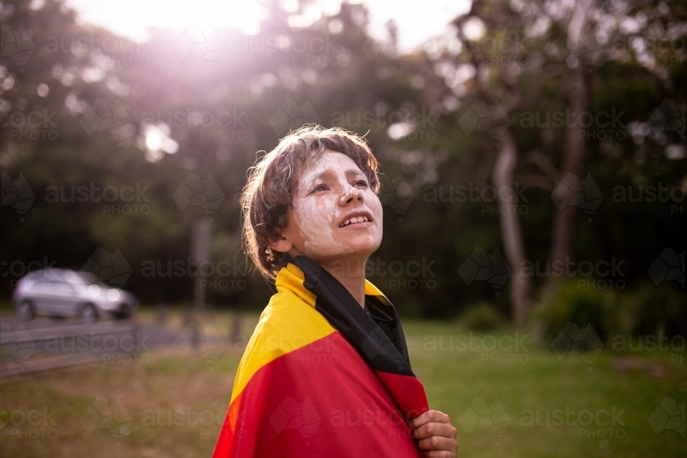 Image of Young Aboriginal boy wearing the Aboriginal flag around his ...