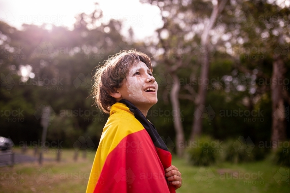 Image of Young Aboriginal boy wearing the Aboriginal flag around his ...