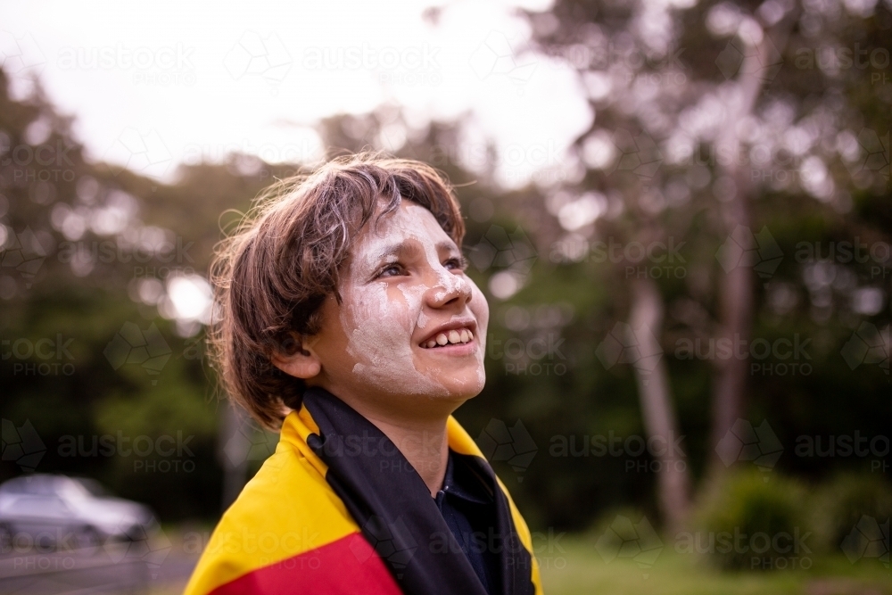 Image of Young Aboriginal boy wearing the Aboriginal flag around his ...