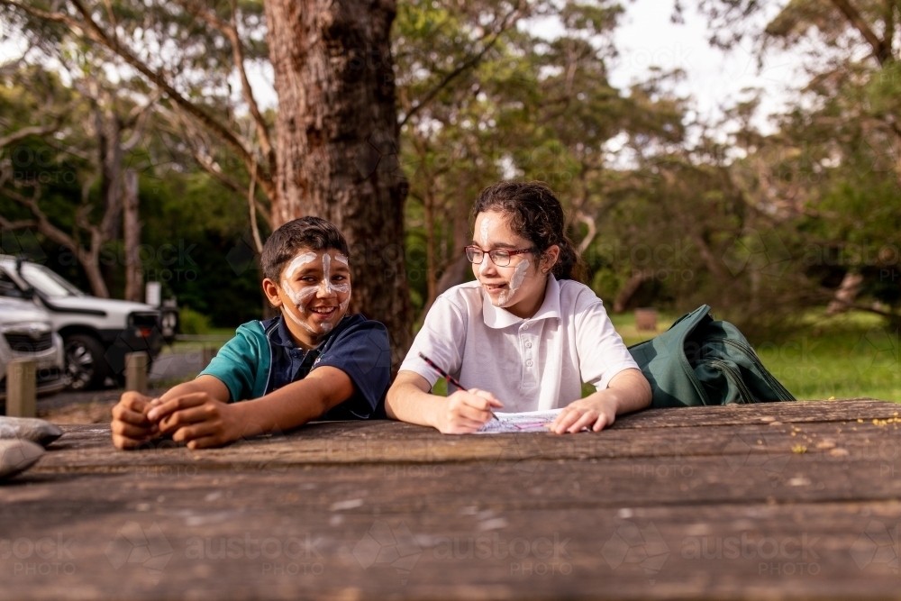 Image of Young Aboriginal children sitting at a table outdoors smiling ...