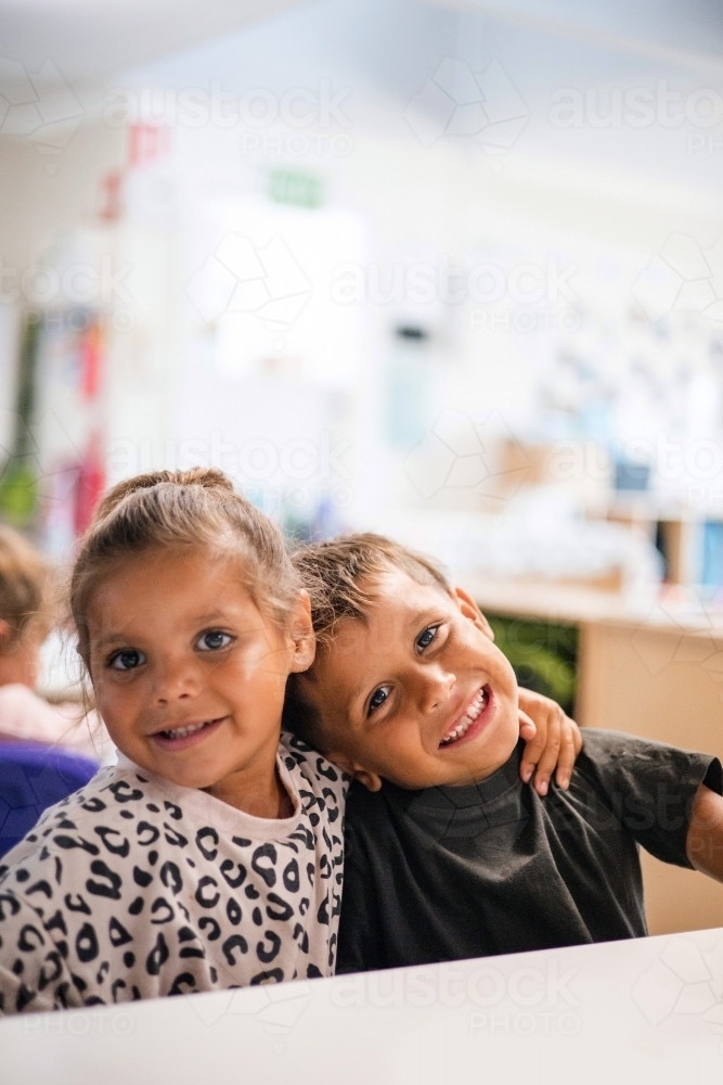 Image of Young Aboriginal girl and boy hugging at preschool - Austockphoto