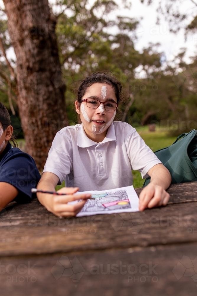 Image of Young Aboriginal girl sitting at an outdoor table drawing and ...