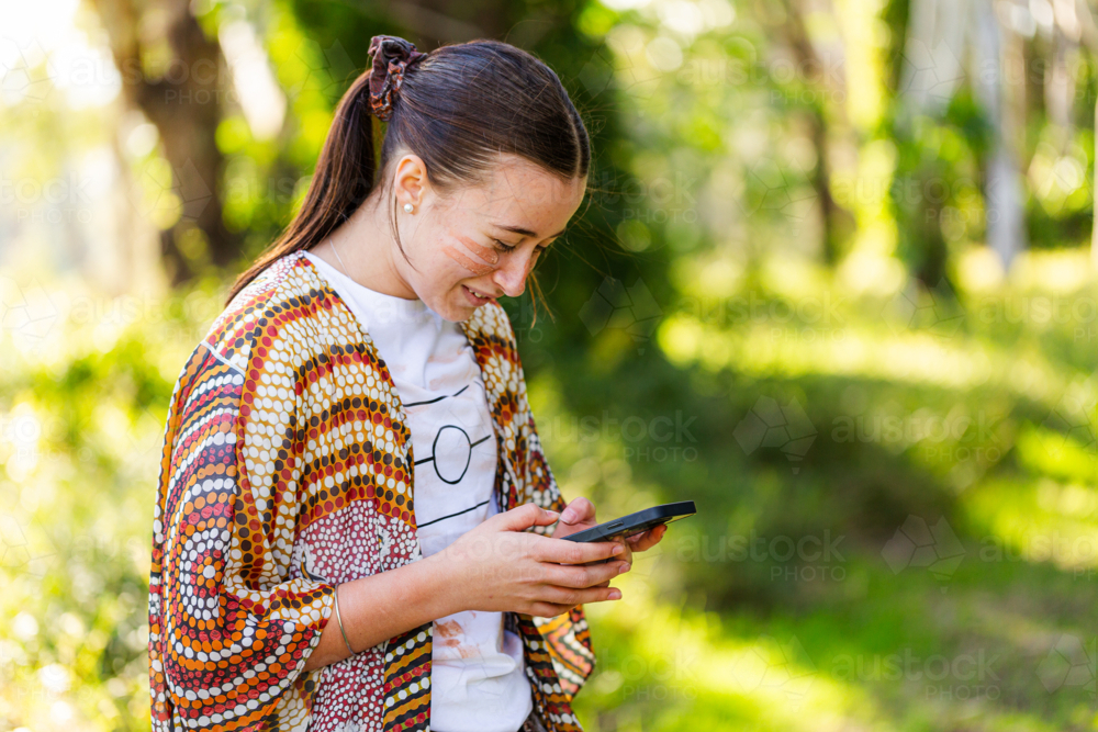 Image of Young aboriginal person typing on mobile phone device ...
