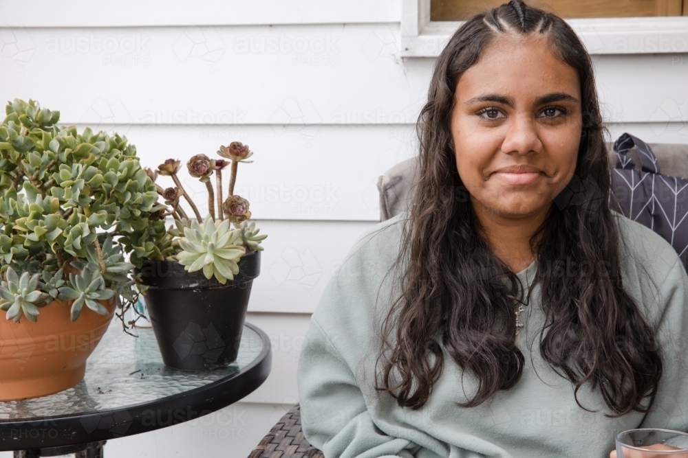 Image of Young Aboriginal woman sitting on a couch outside - Austockphoto