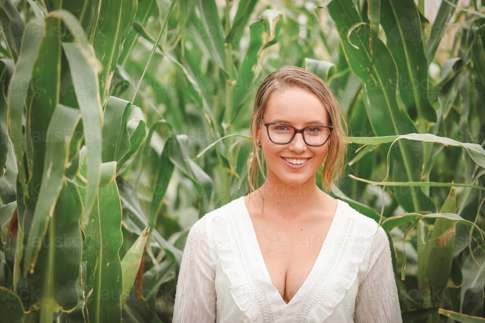 Image of Young adult woman standing in rural corn crop - Austockphoto
