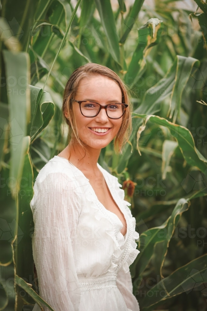 Image of Young adult woman standing in rural corn crop - Austockphoto