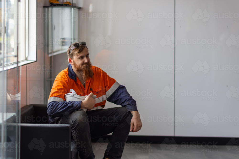 Image of Young adult worker sitting on the couch inside the office ...