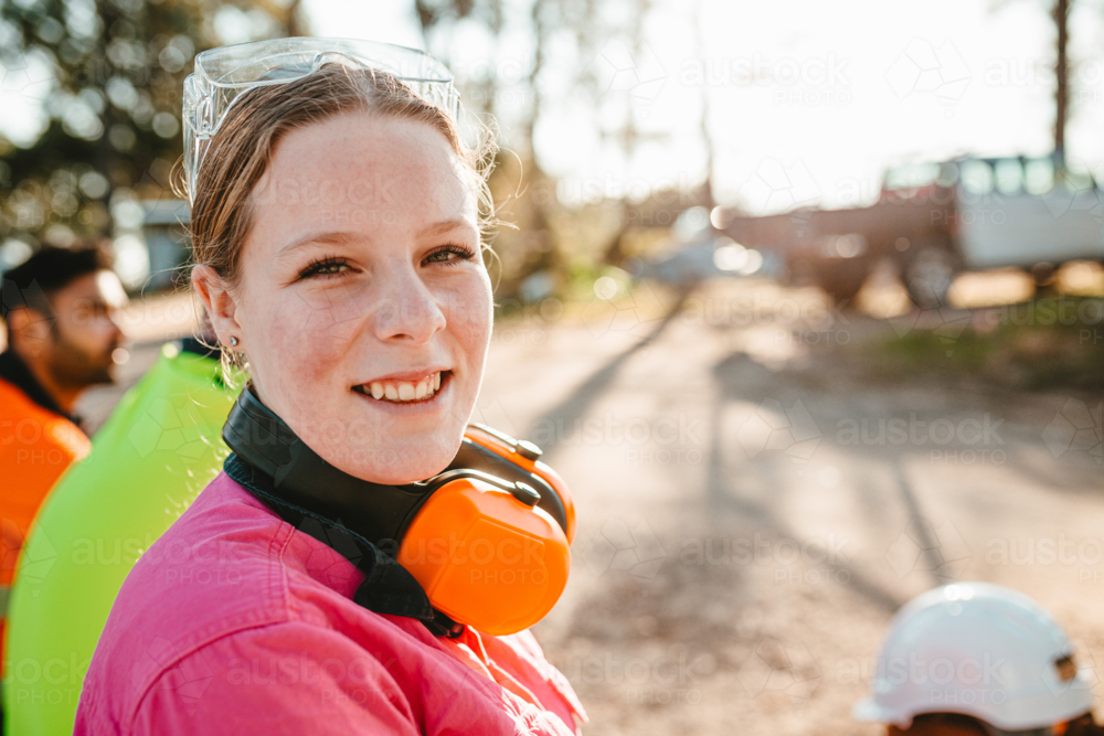 Image of Young apprentice woman smiling while sitting with colleagues ...