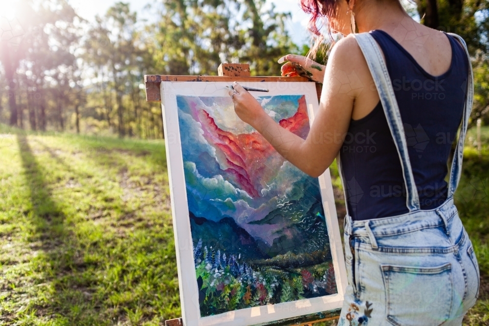 Image of Young artist in overalls painting art outside in nature ...