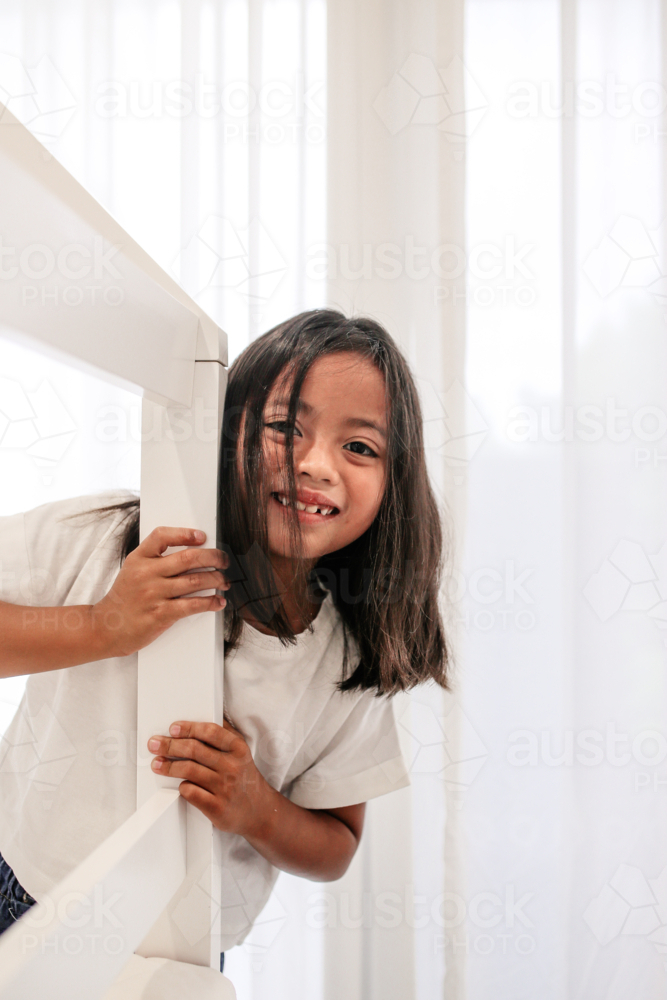 Image of Young Asian girl clinging on the pole of the bunkbed ...