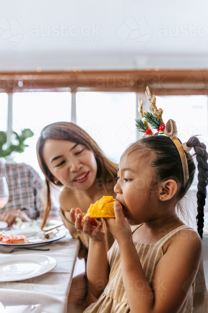 Image of Young Asian girl eating fresh ripe mango. - Austockphoto