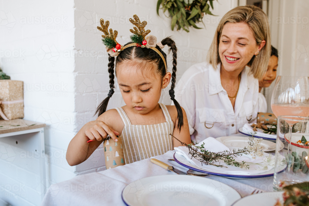 Image of Young Asian girl holding a Christmas cracker looking down ...