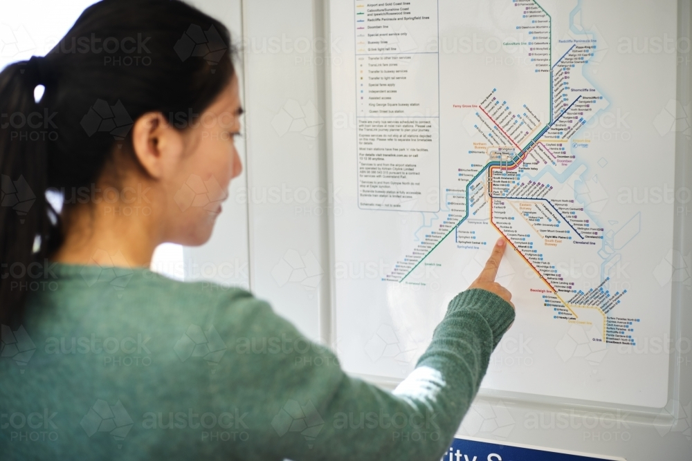 Image of Young Asian woman pointing on the train map. - Austockphoto