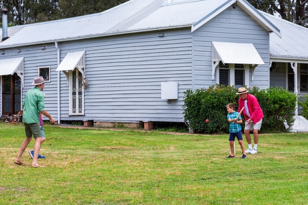 Image of Young aussie boys playing backyard cricket with dad and ...