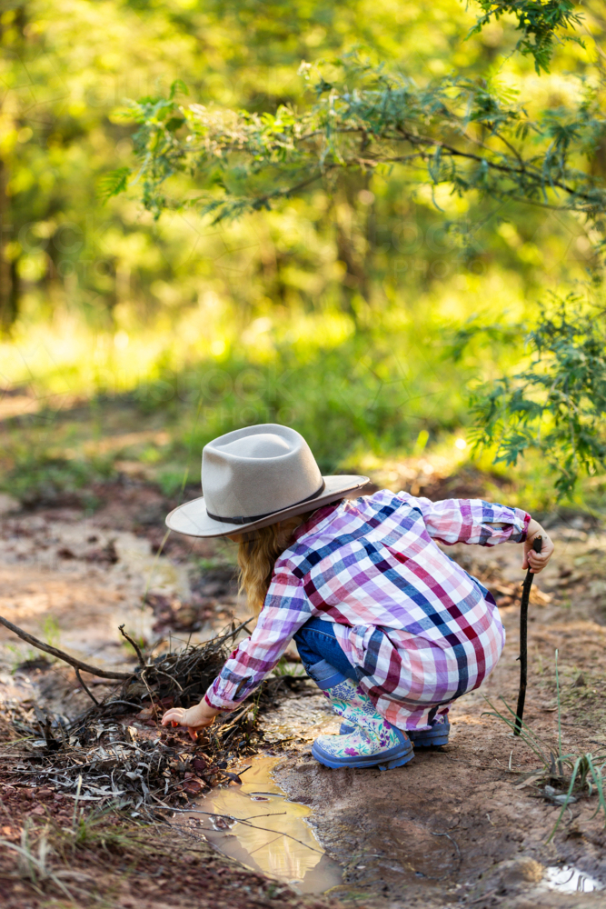Image of Young Aussie kid exploring bushland playing in muddy water ...