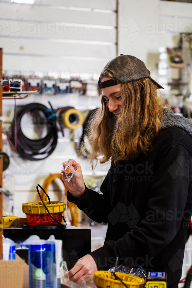 Image of young aussie mechanic working on rewiring light electronics ...