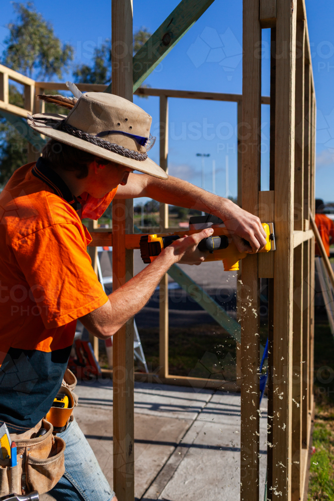 Image of young Aussie tradie using planer tool on frame of building to ...